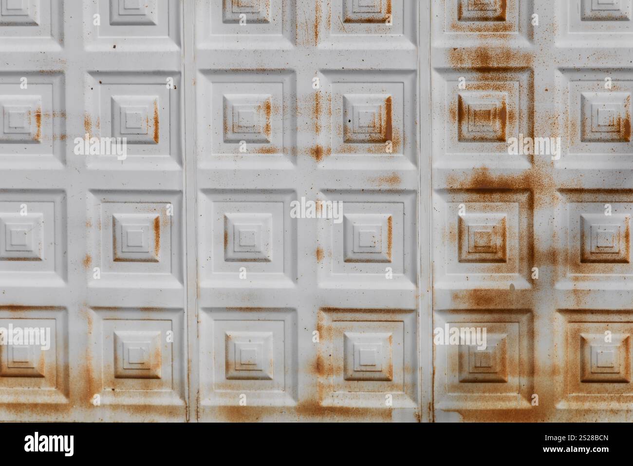 A white door weathered by rust, showing signs of wear and aging. The ...