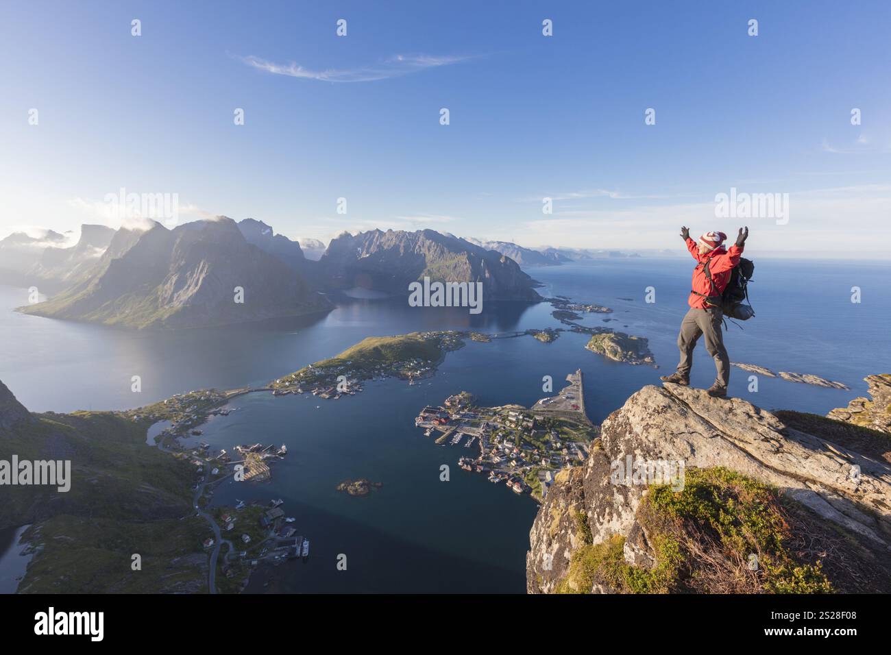 NORWAY. LOFOTEN ISLANDS. REINEBRINGEN. MOSKENES A HIKER ADMIRES THE SEA ...