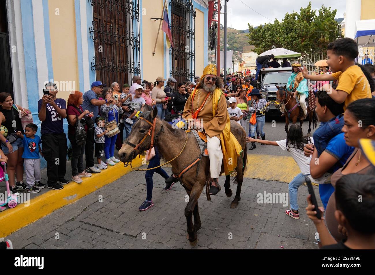 A man dressed as one of the Three Kings parades through a street during ...