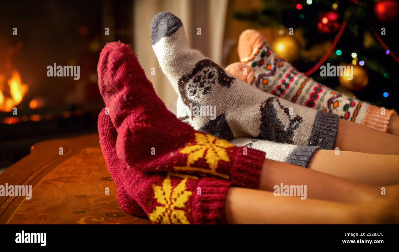 Closeup image of family feet in warm socks lying next to Christmas tree ...