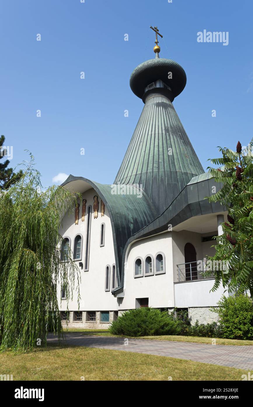 Modern church with striking green roof and windows surrounded by trees ...