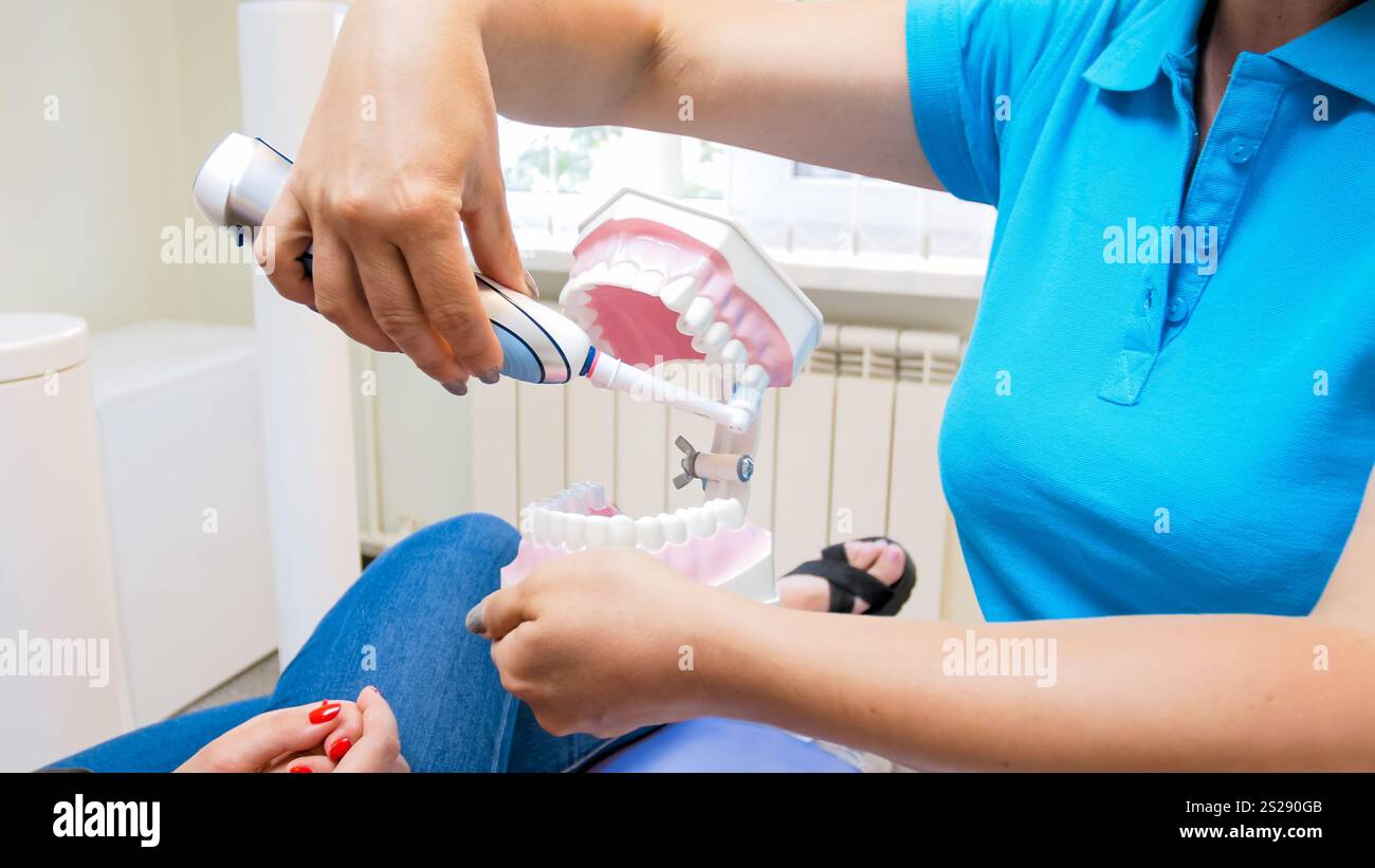 Closeup photo of dentist showing patient how to use electric toothbrush ...