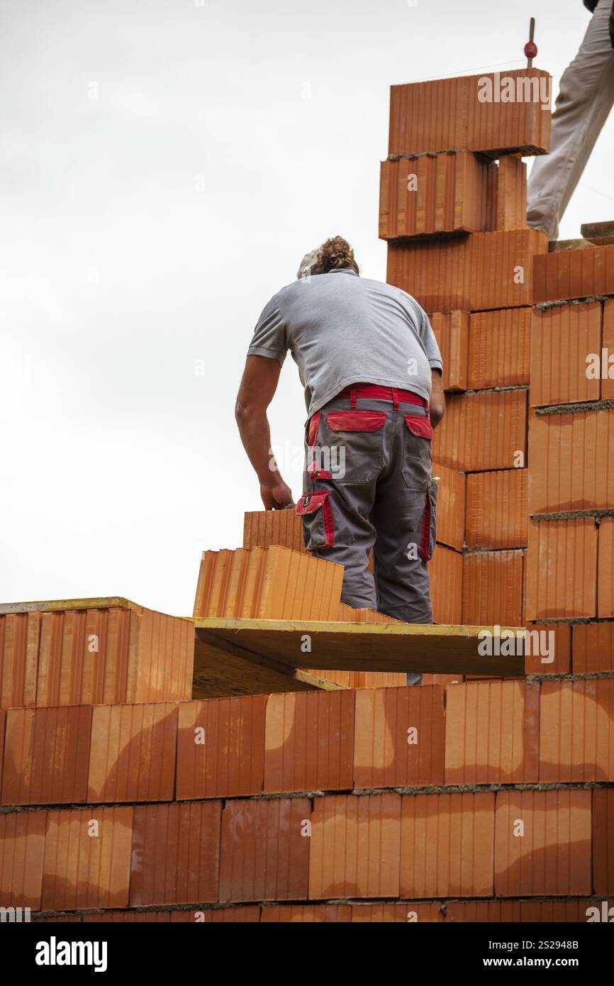 Anonymous construction worker on a building site erecting a brick wall ...