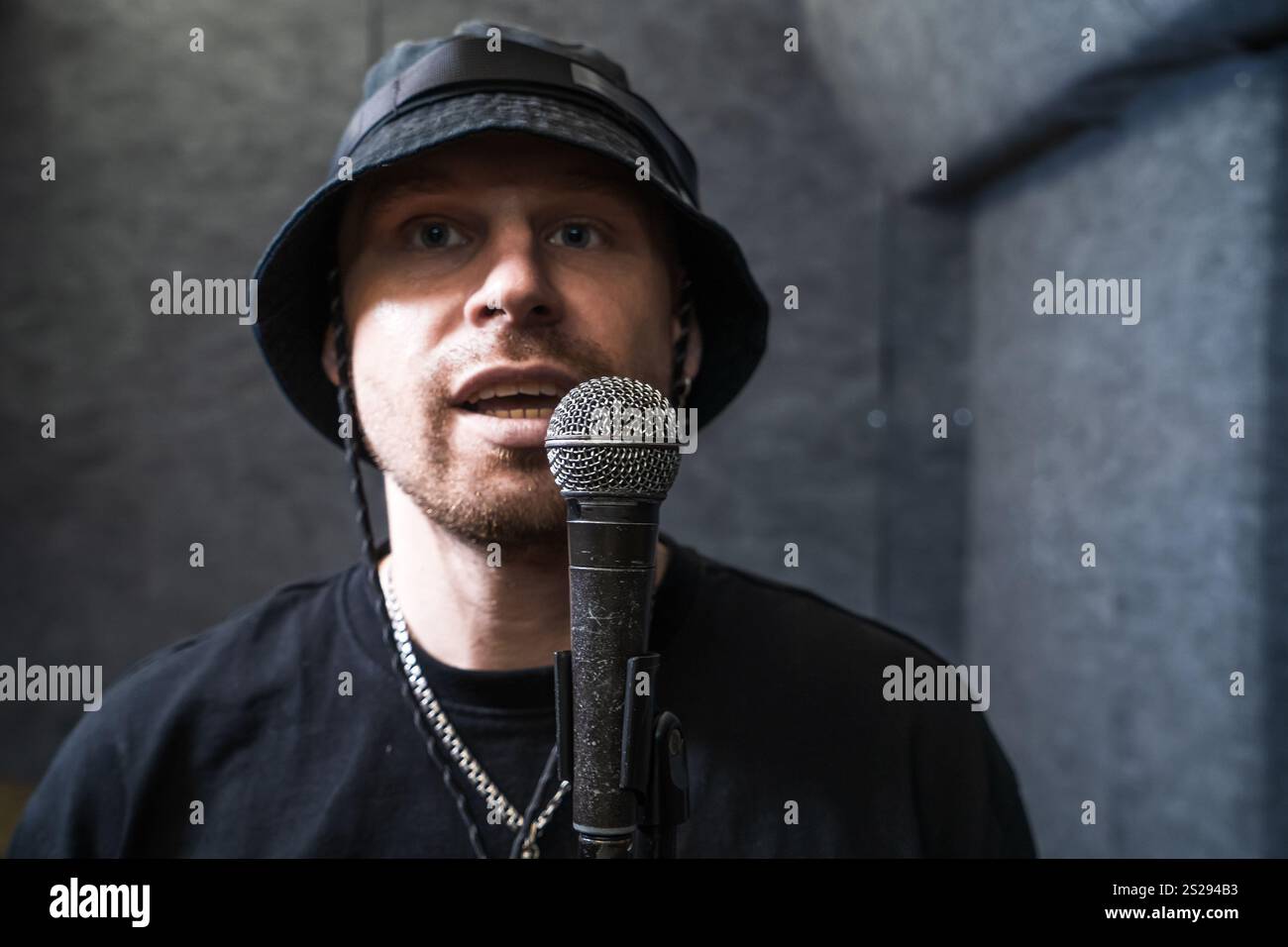 Rapper wearing black bucket hat performing into microphone in music ...