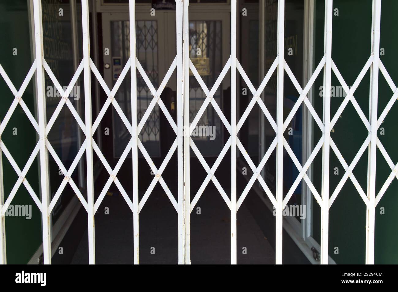 A shop is closed by a scissor gate. Symbol photo for shop opening hours ...