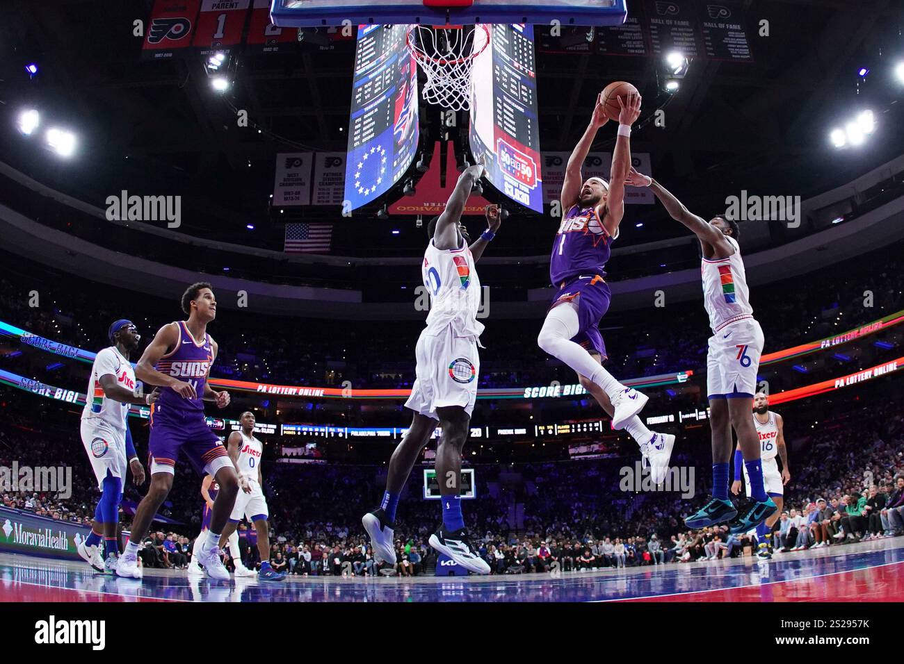 Phoenix Suns' Devin Booker, center, goes up for a shot between ...