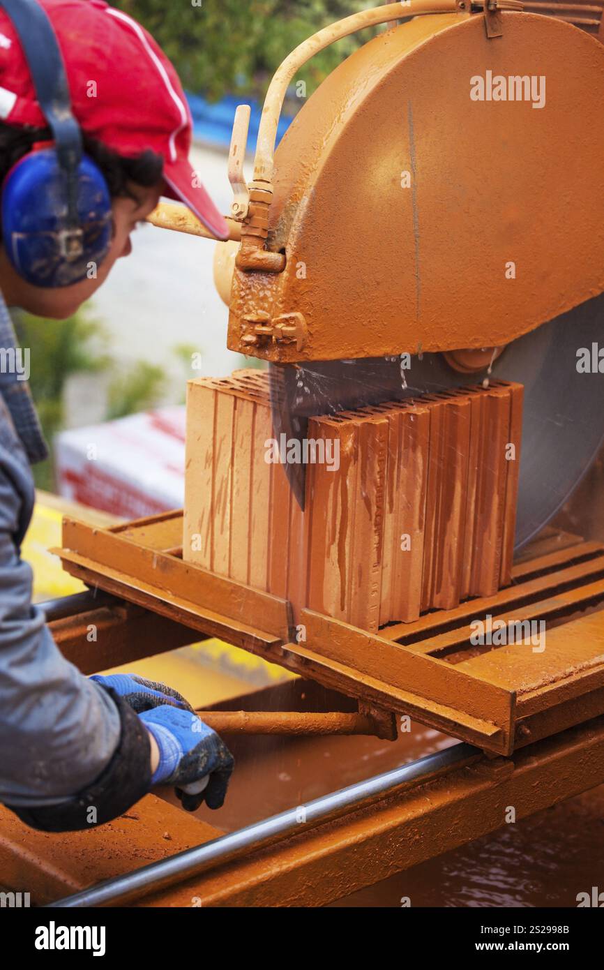 Construction worker cuts bricks for the construction of a detached house in solid construction ...