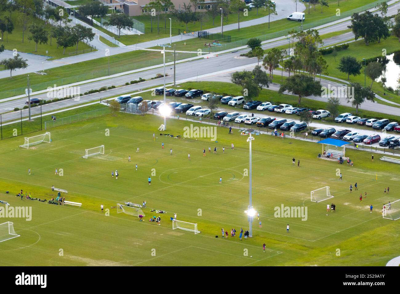Public sports stadium with school kids playing football game at sunset ...