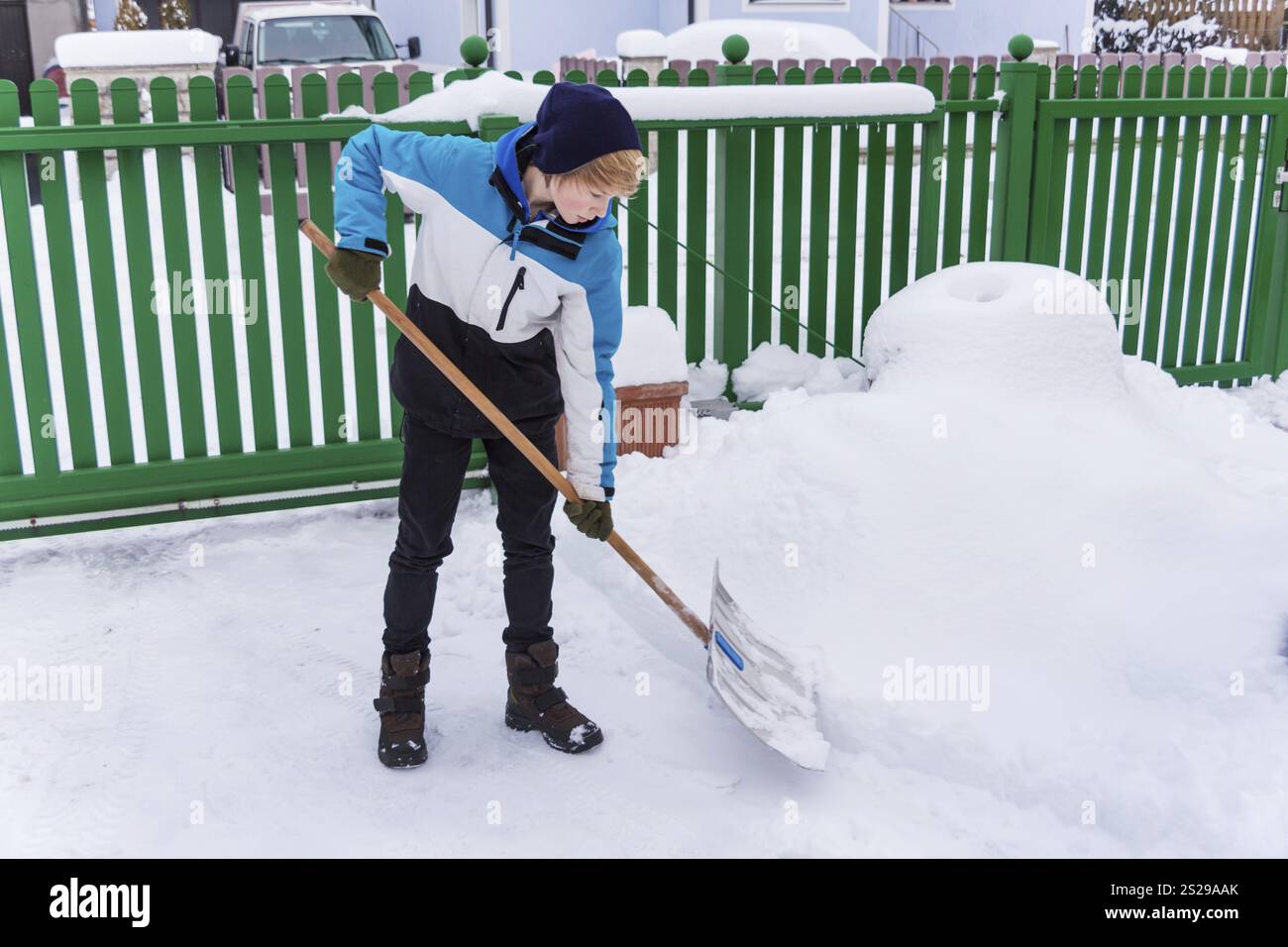 A teenager shovels the new snow from a path. Onset of winter in Austria ...