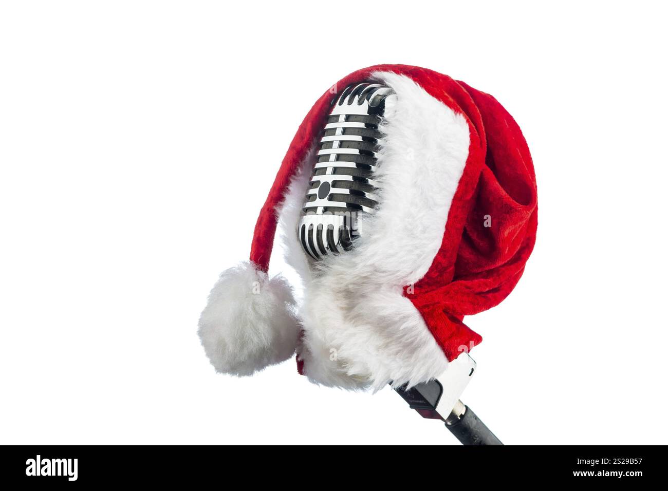 An old retro microphone with a Christmas hat in front of a red velvet ...