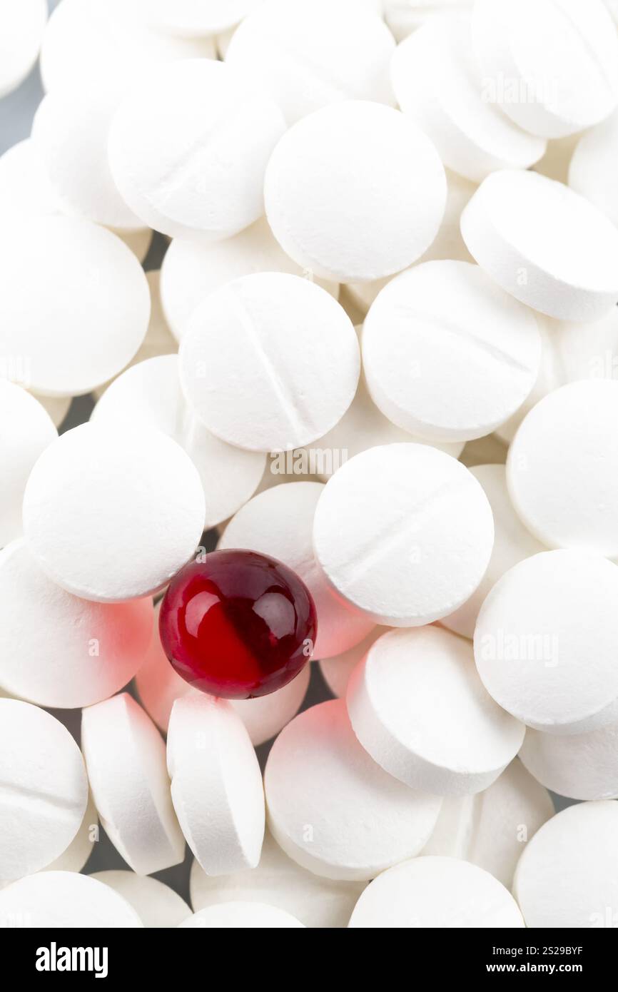 White tablets in contrast with a red tablet, symbolic photo for ...