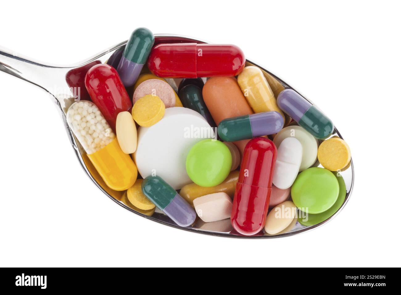 Many different coloured tablets on a spoon. Abuse of medication ...