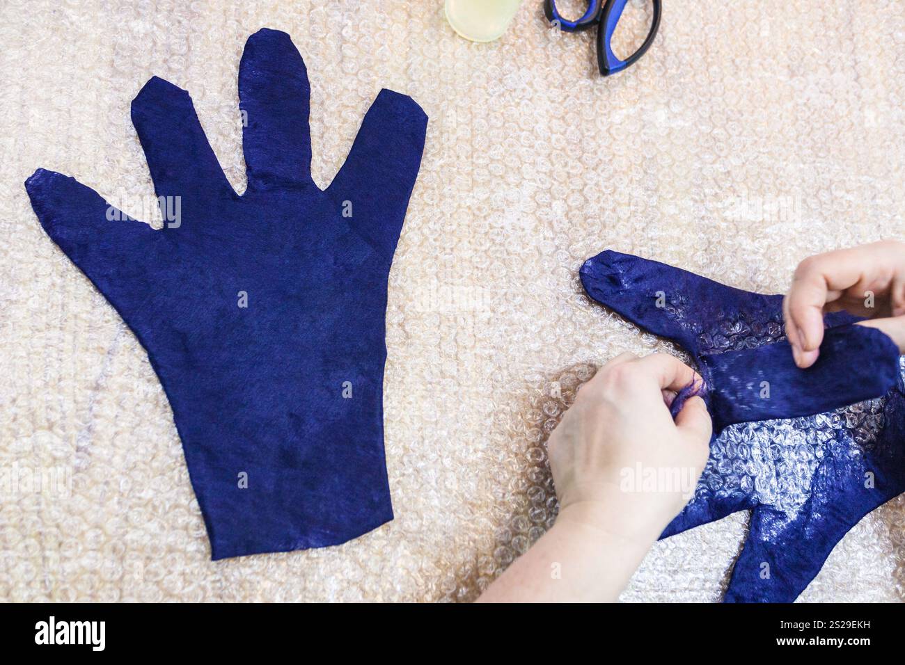 workshop of hand making a fleece gloves from blue Merino sheep wool ...