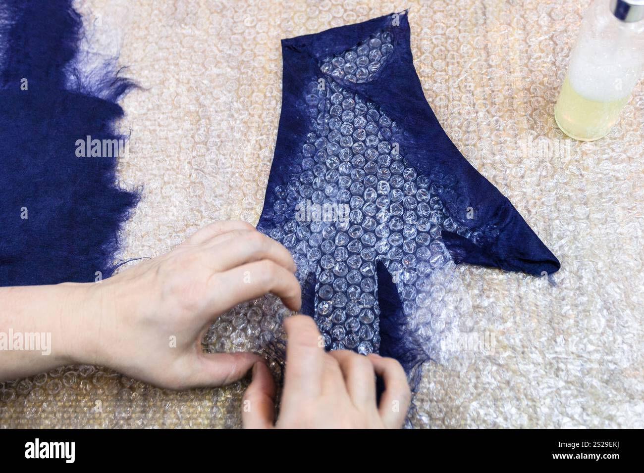 workshop of hand making a fleece gloves from blue Merino sheep wool using wet felting process ...