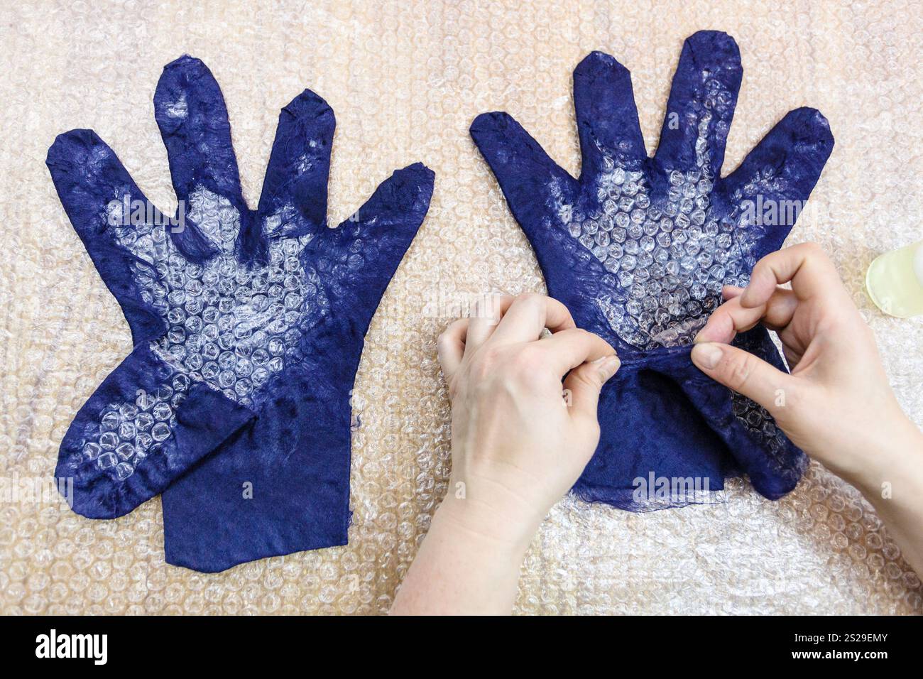 workshop of hand making a fleece gloves from blue Merino sheep wool ...