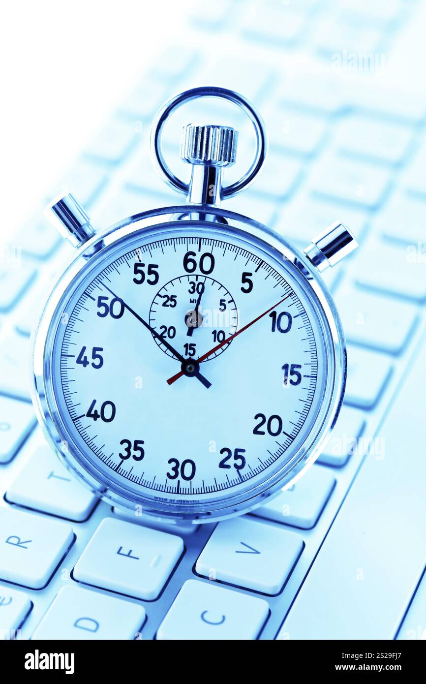 A stopwatch lies on the keyboard of a computer. Working time in the ...