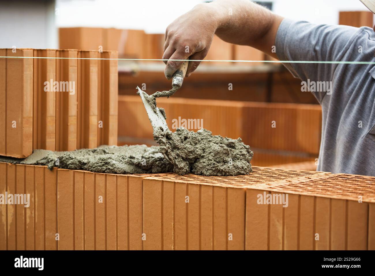 Anonymous construction worker on a building site erecting a brick wall ...