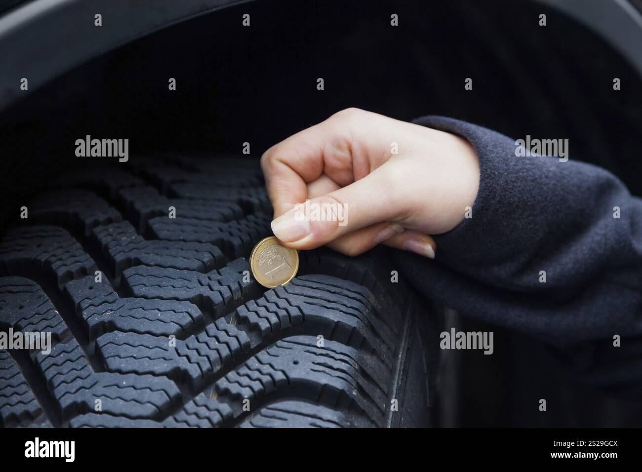 A young woman measures the tread depth of her car tyre. The right depth ...