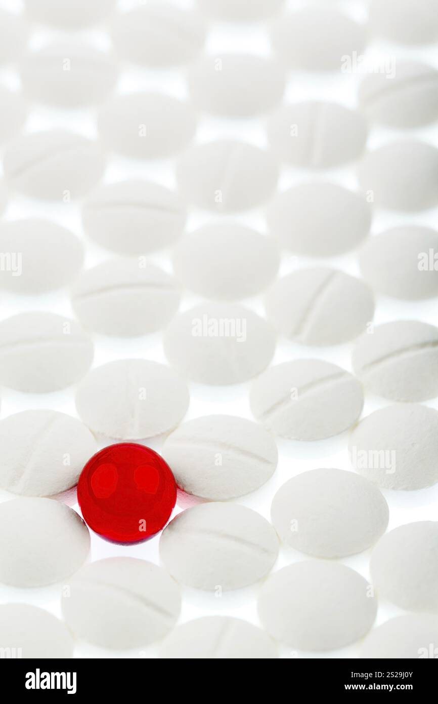 White tablets in contrast with a red tablet, symbolic photo for ...