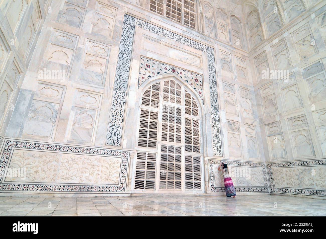 A tourist taking a photo of the detailed patterns in the white marble ...
