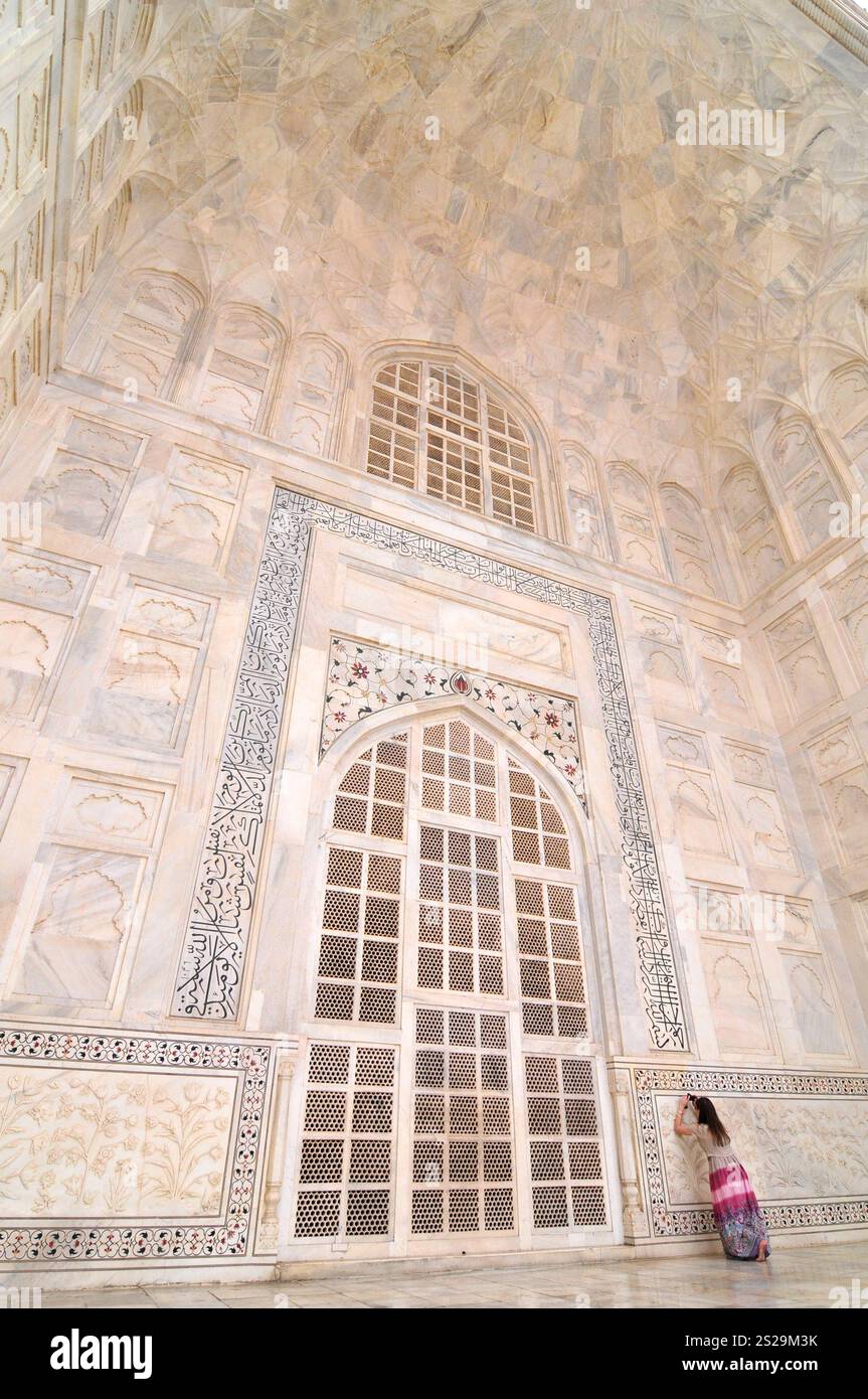 A tourist taking a photo of the detailed patterns in the white marble ...