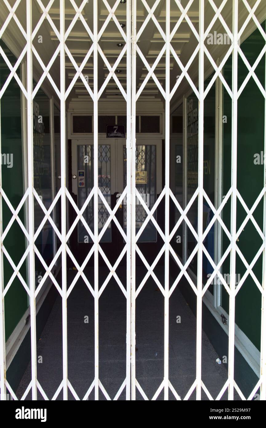 A shop is closed by a scissor gate. Symbol photo for shop opening hours ...