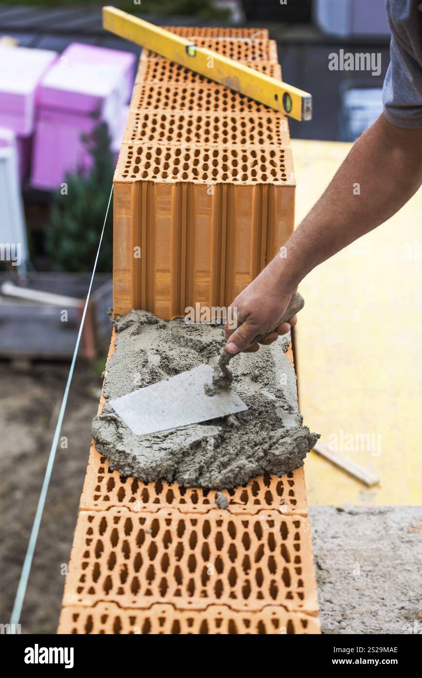 Anonymous construction worker on a building site erecting a brick wall ...