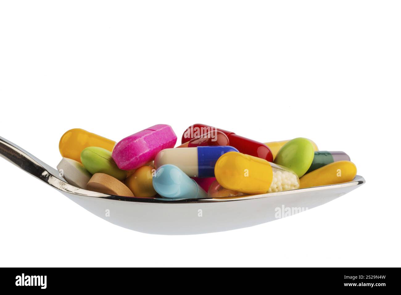 Many colourful tablets on a spoon. Symbolic photo for tablet addiction ...