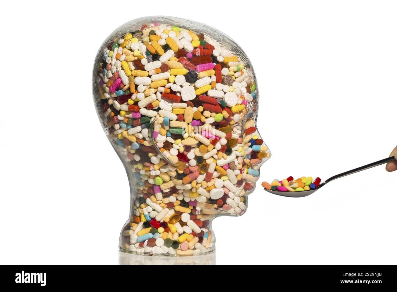 A glass head filled with many tablets. Symbolic photo for medication ...
