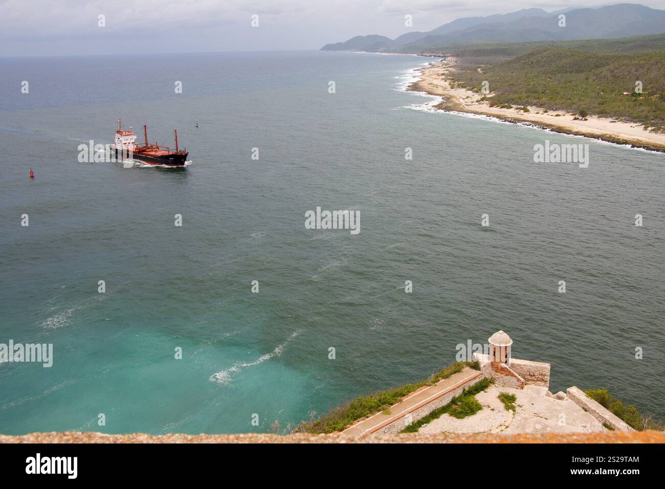 A Large cargo boat entering Santiago de cuba bay entrance and a turret ...