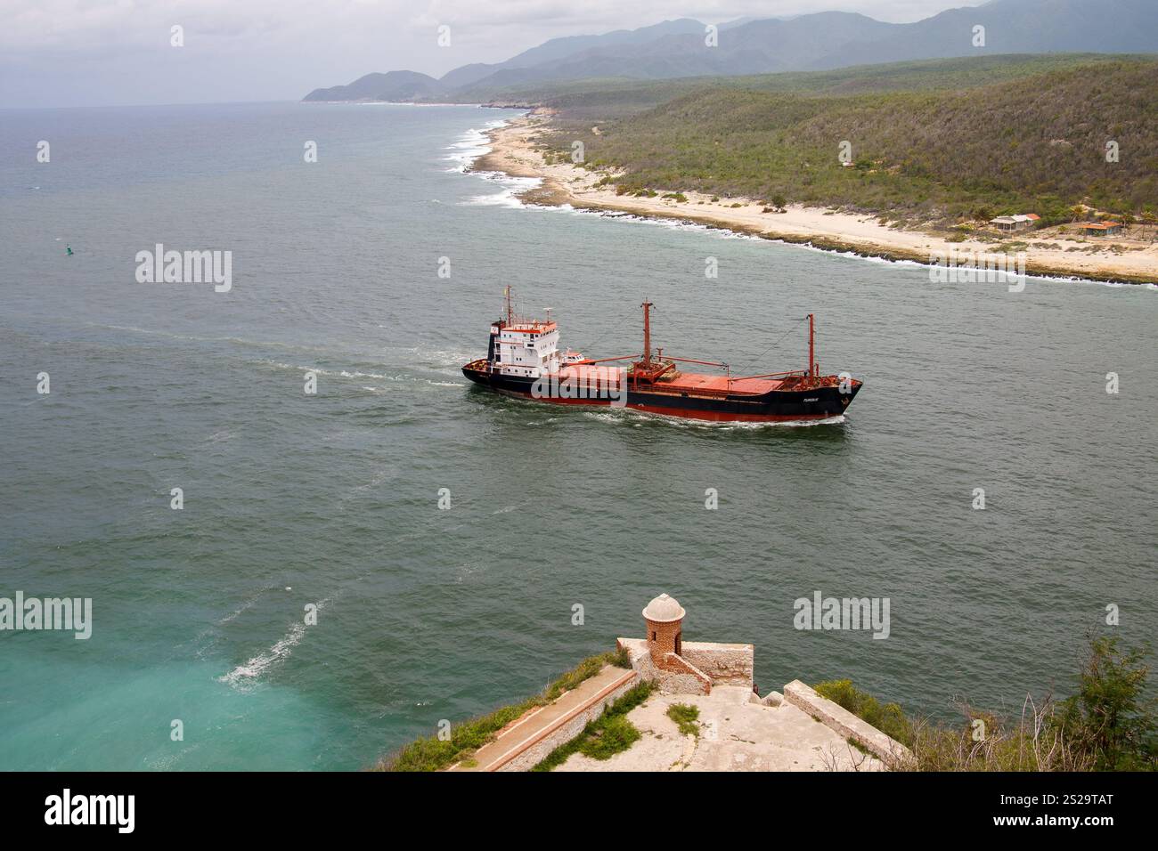 A Large cargo boat entering Santiago de cuba bay entrance and a turret ...