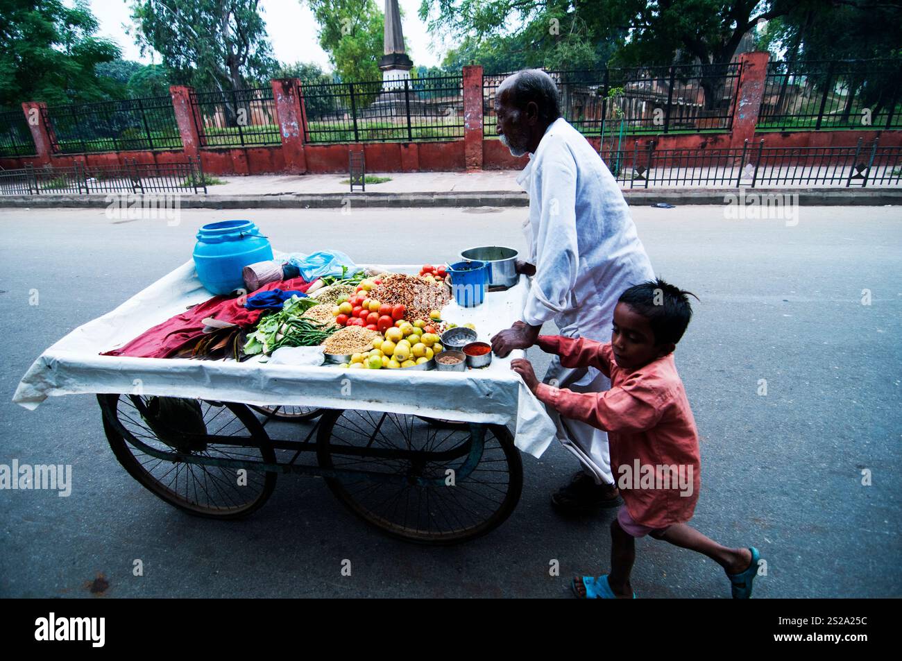 A man and his grandchild pushing their vegetable cart by the Residency ...