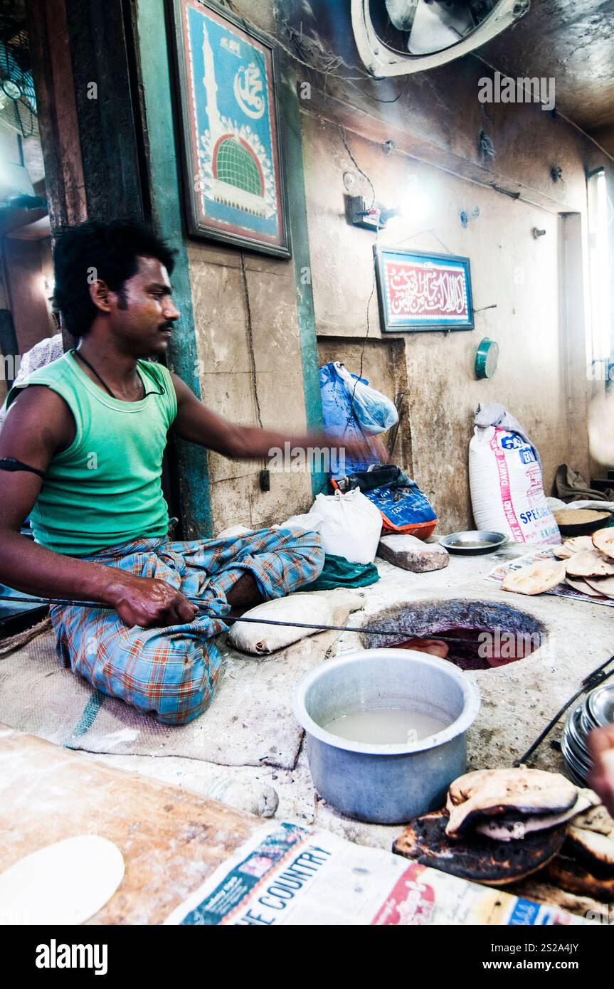 A Man baking roti breads in a tandoor oven in a small bakery at the ...