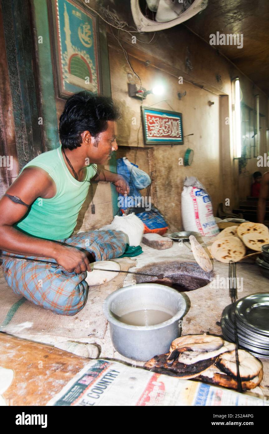 A Man baking roti breads in a tandoor oven in a small bakery at the ...