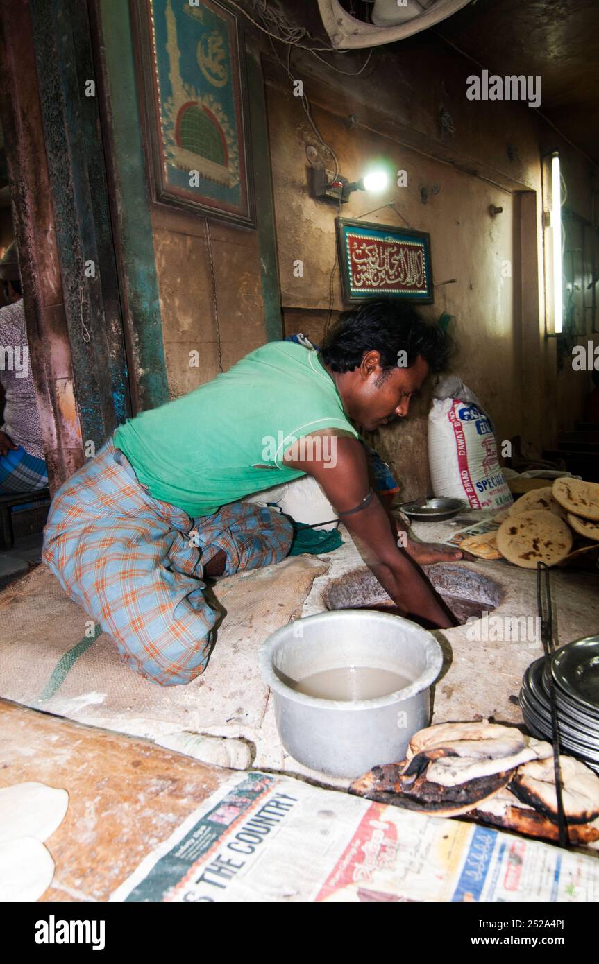 A Man baking roti breads in a tandoor oven in a small bakery at the ...