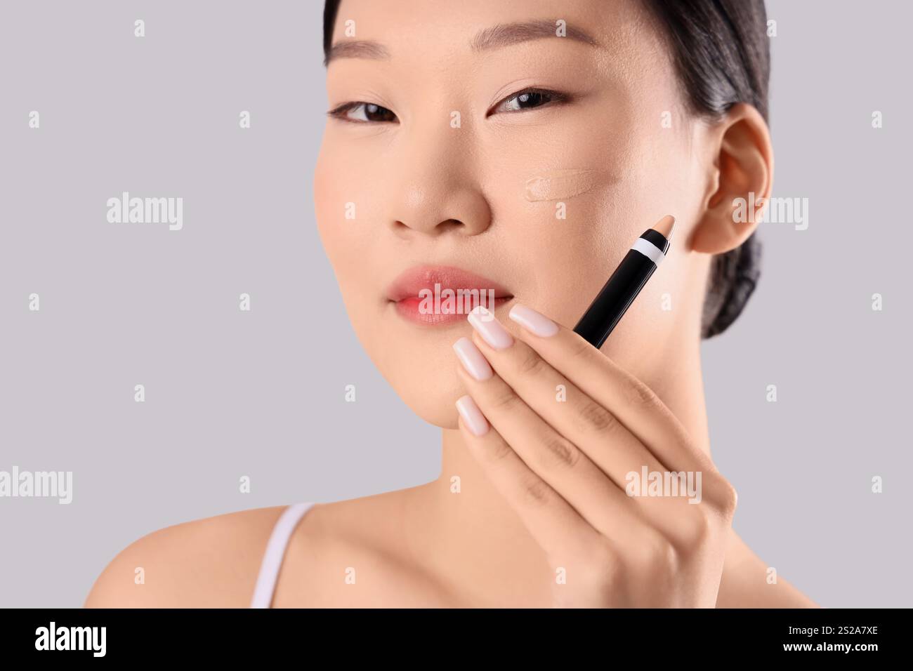 Beautiful Asian woman with tonal foundation on grey background Stock ...