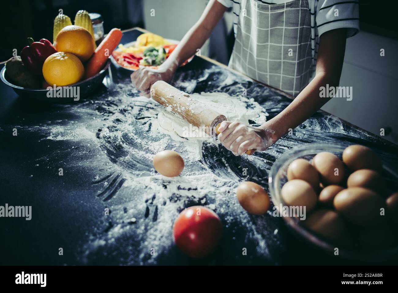 Little chef using rolling pin stretching the dough. Cooking concept ...