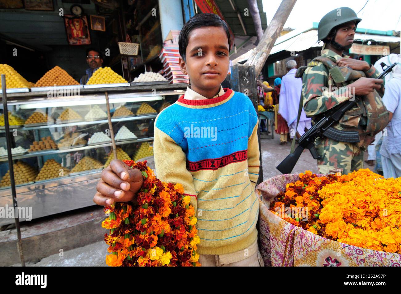 An Indian soldier standing by a young flower garland vendor near ...