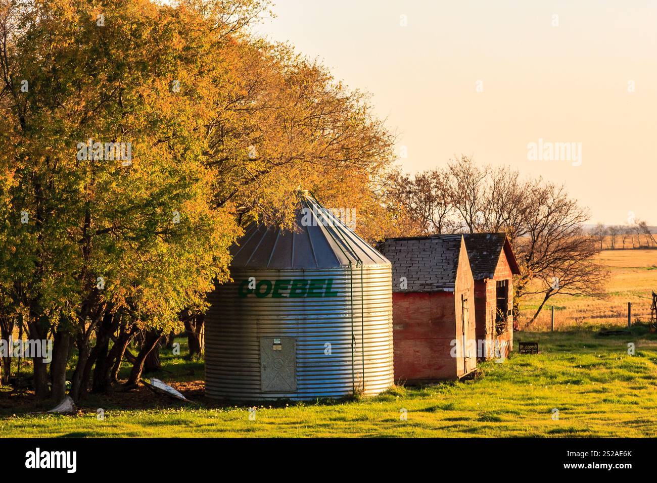 A farm with a large metal silo and two small buildings. The silo is ...