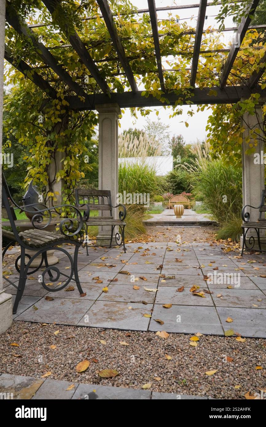 Wooden garden chairs and fallen leaves on flagstone patio underneath ...