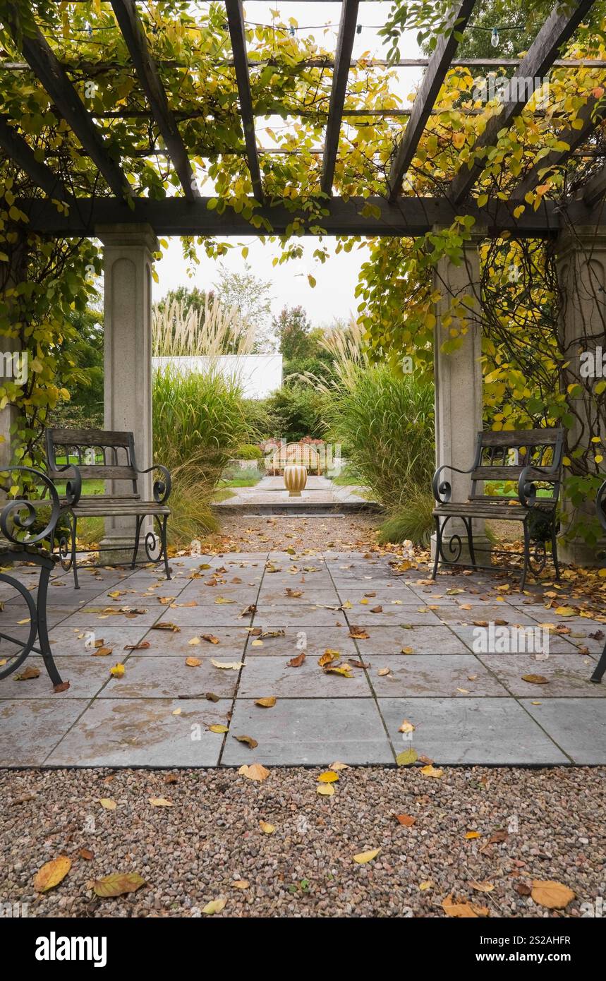 Wooden garden chairs and fallen leaves on flagstone patio underneath ...