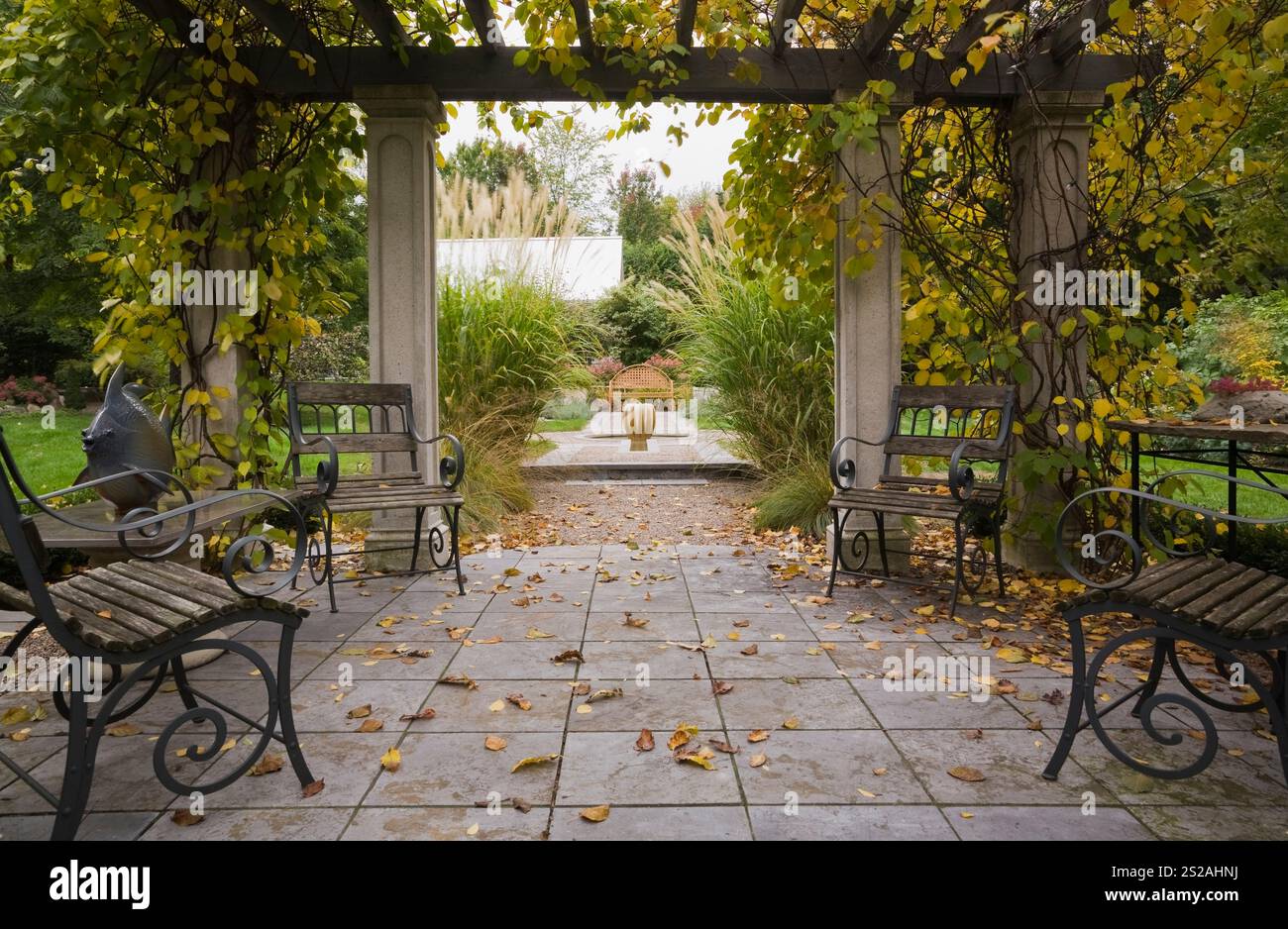 Wooden garden chairs and fallen leaves on flagstone patio underneath ...