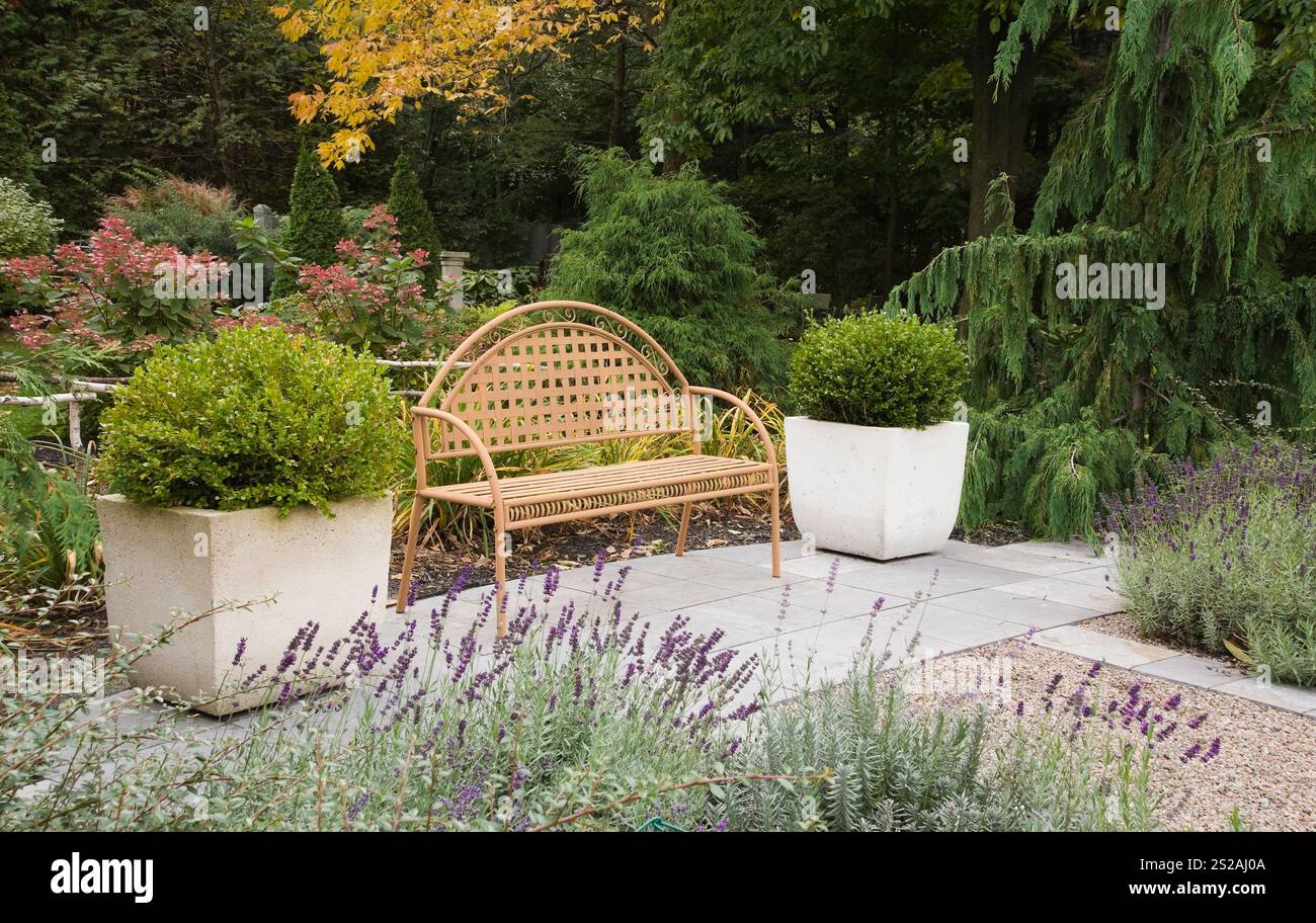 Gravel bed and light brown metal lattice garden bench next to concrete ...