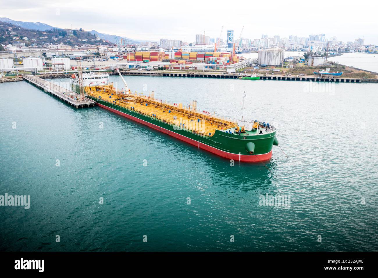 Large oil tanker moored in busy harbor with cargo containers, capturing ...