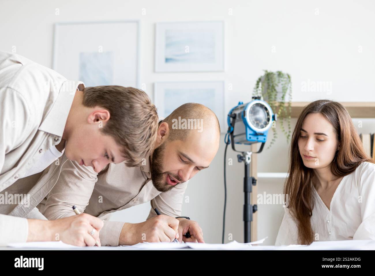 Script writing. Studio team. Girl watches as men taking notes sign ...