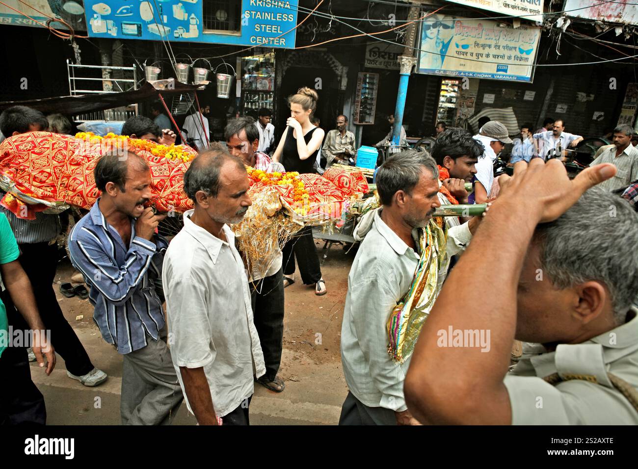 Men carrying a body as they are walking on a busy road, heading to one ...