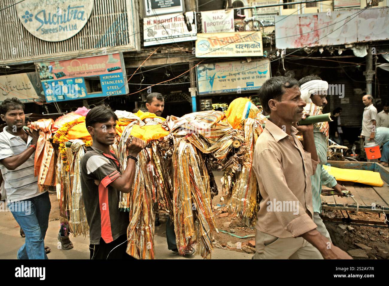 Men carrying a body as they are walking on a busy road, heading to one ...