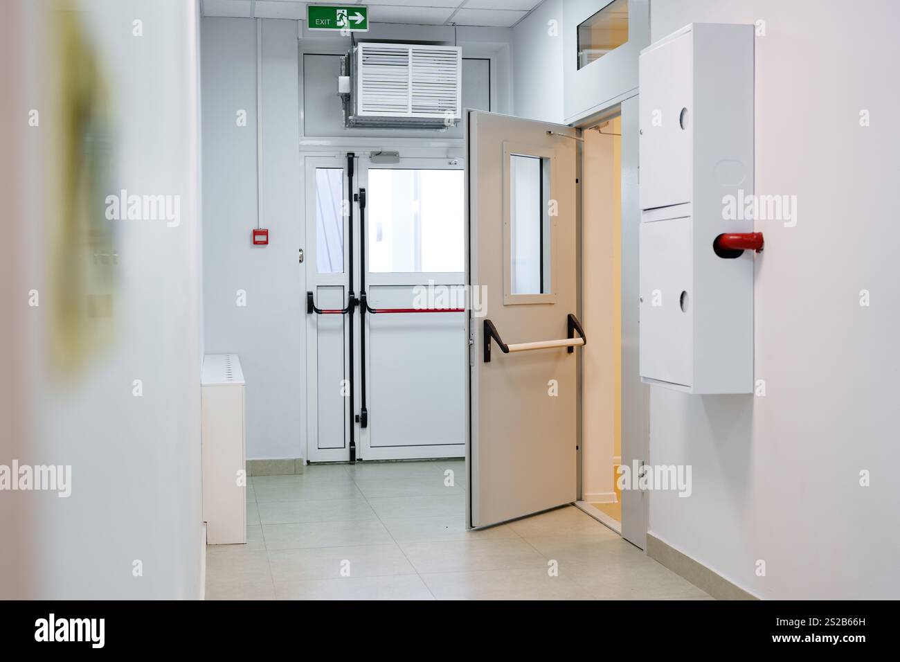 Interior corridor with an open door leading to an exit in a modern ...