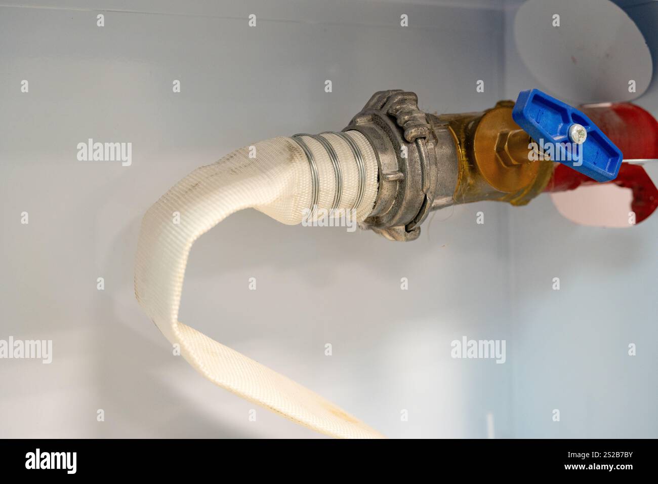 Pipe connection in a plumbing system with a visible hose and valve in a ...