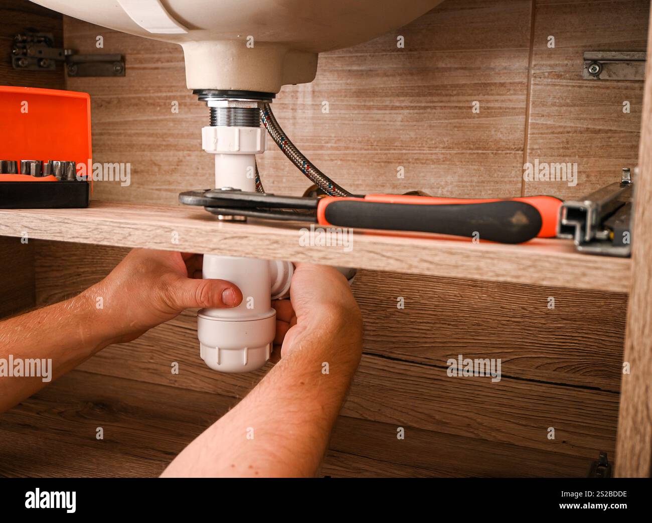 Professional plumber working under sink, fixing pipes and installing ...